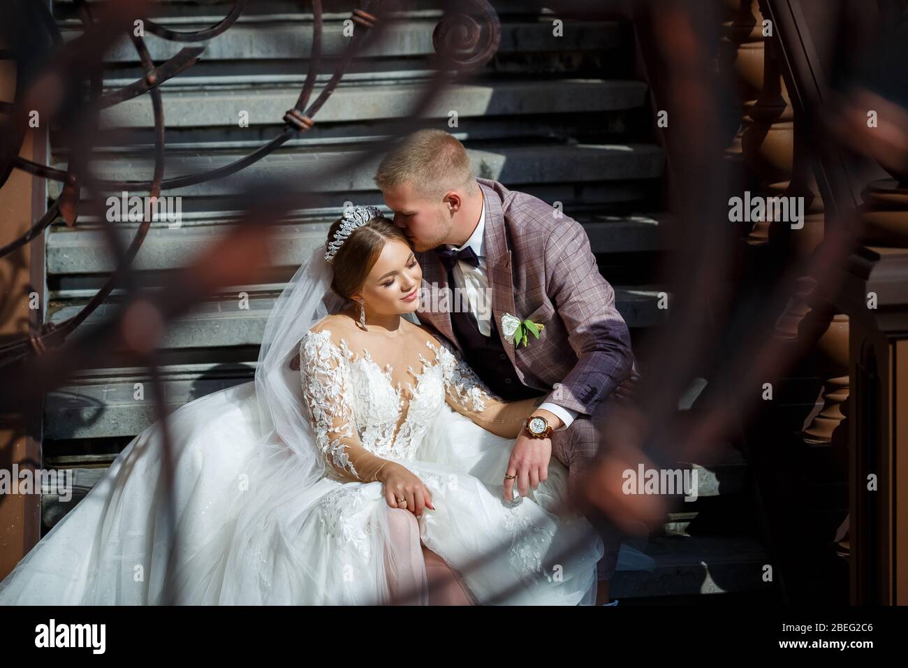 Bride in white dress and groom in costumes hug on the steps Stock Photo ...