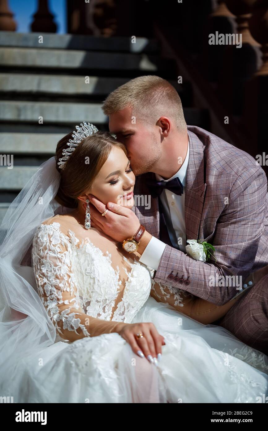 Bride in white dress and groom in costumes hug on the steps Stock Photo ...
