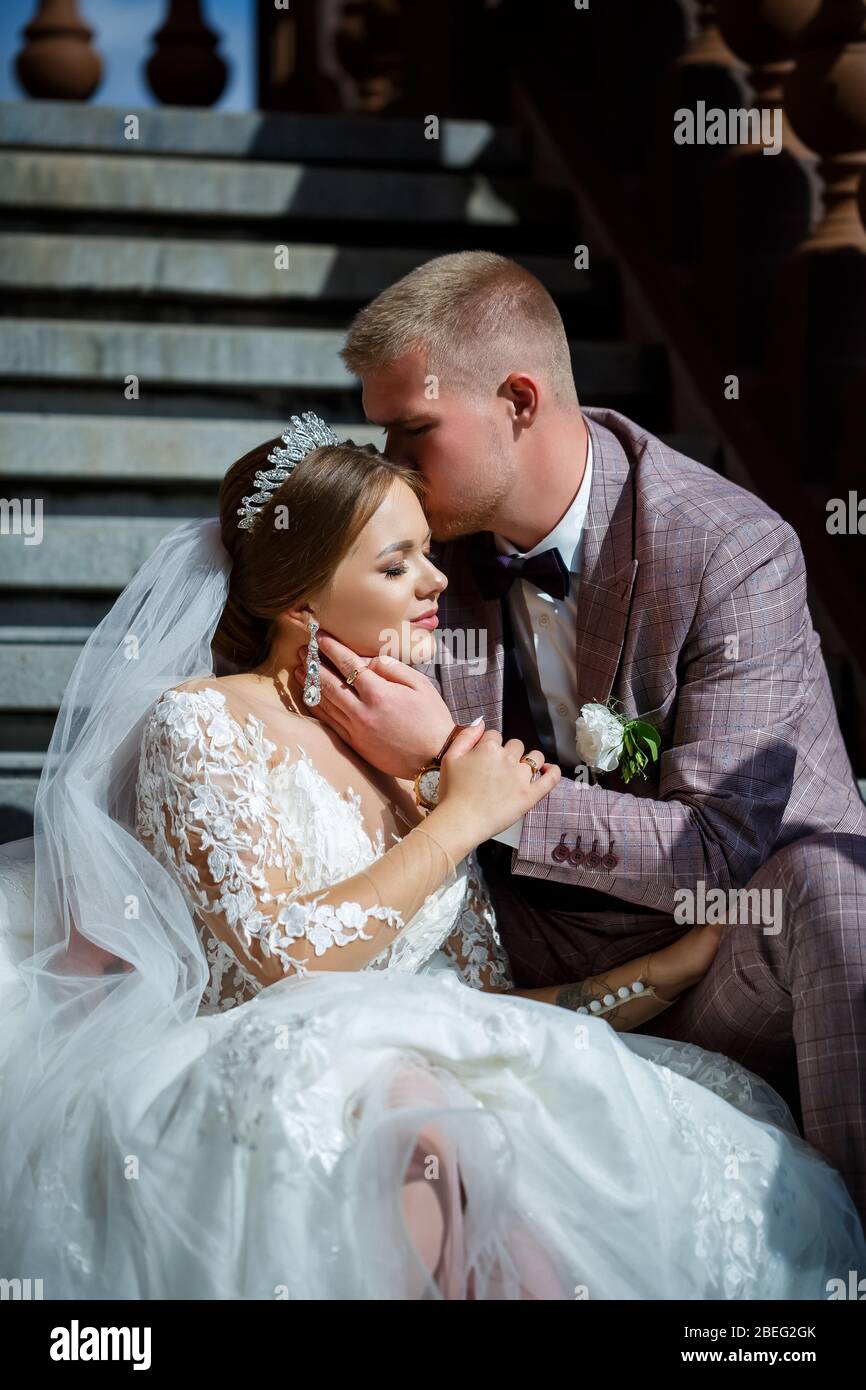 Bride in white dress and groom in costumes hug on the steps Stock Photo ...