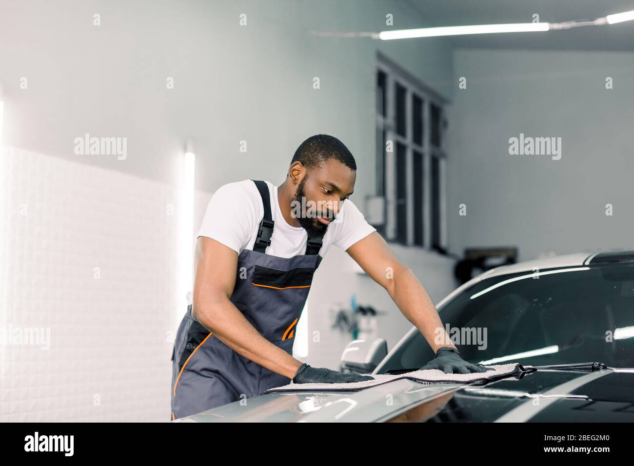 Young handsome African car wash worker man, wearing protective clothes ...