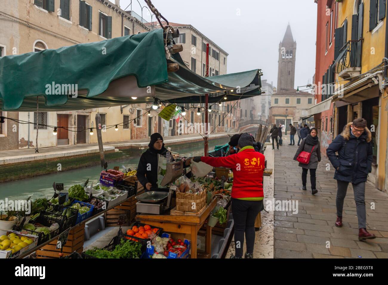 Venice, Italy. January 9th, 2019. People buying on a local grocery shop a boat on a venetian ...