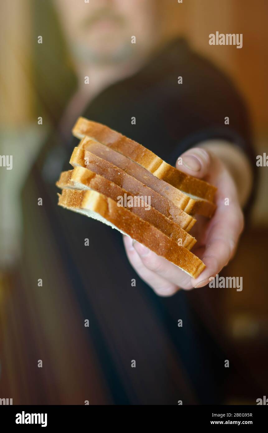 A man shares food. A male hand holds out pieces of bread into the ...