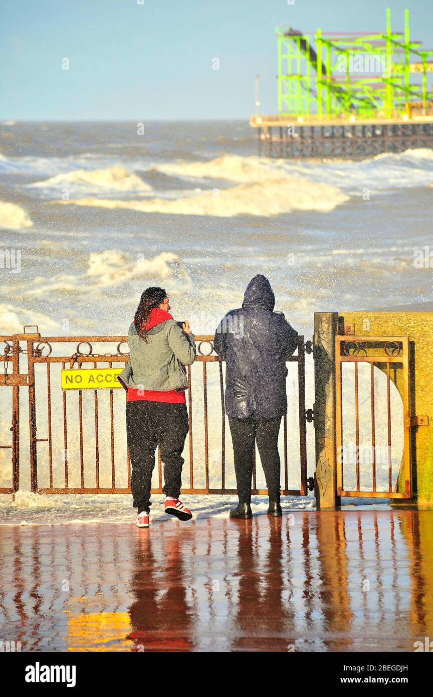 Two young women getting wet photographing the rough sea at Blackpool ...