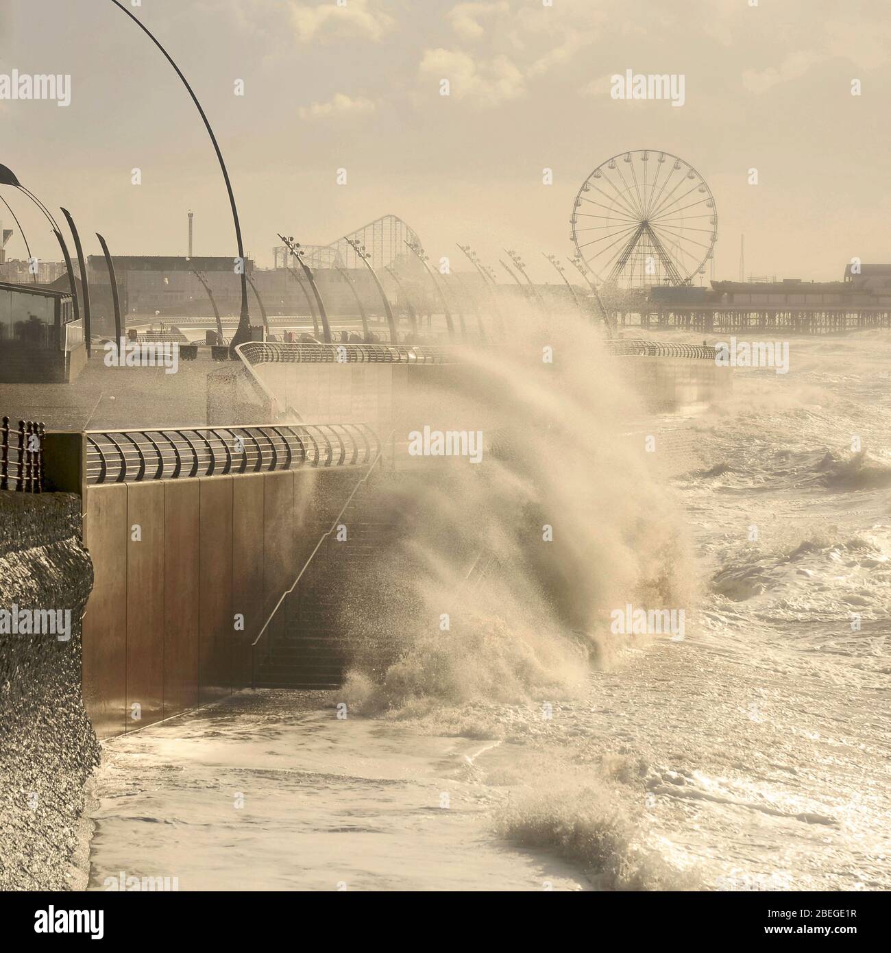 Waves break over the seawall on an empty seafront during wild and windy ...