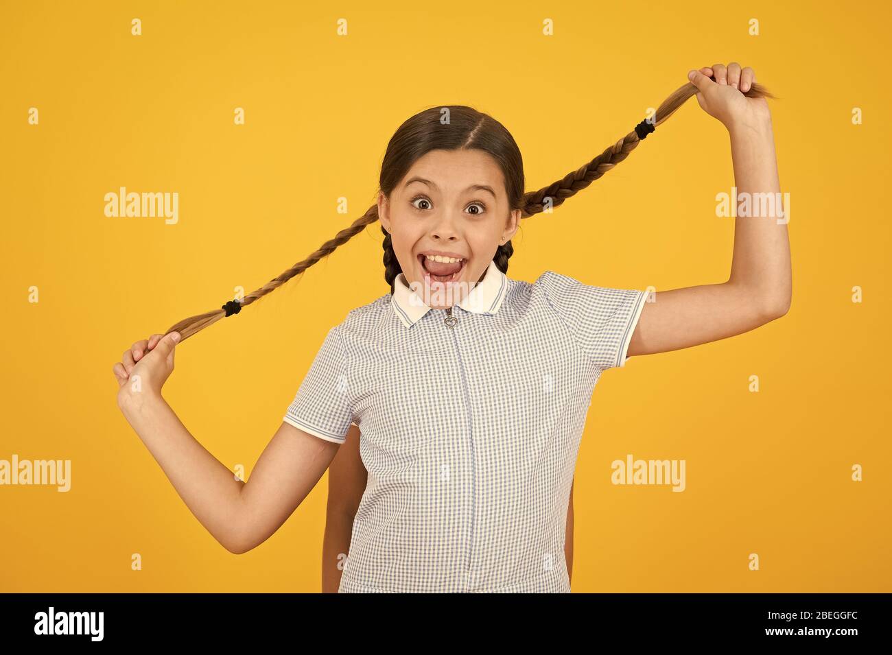 small girl in school uniform. retro look. child hold pigtail of girl ...