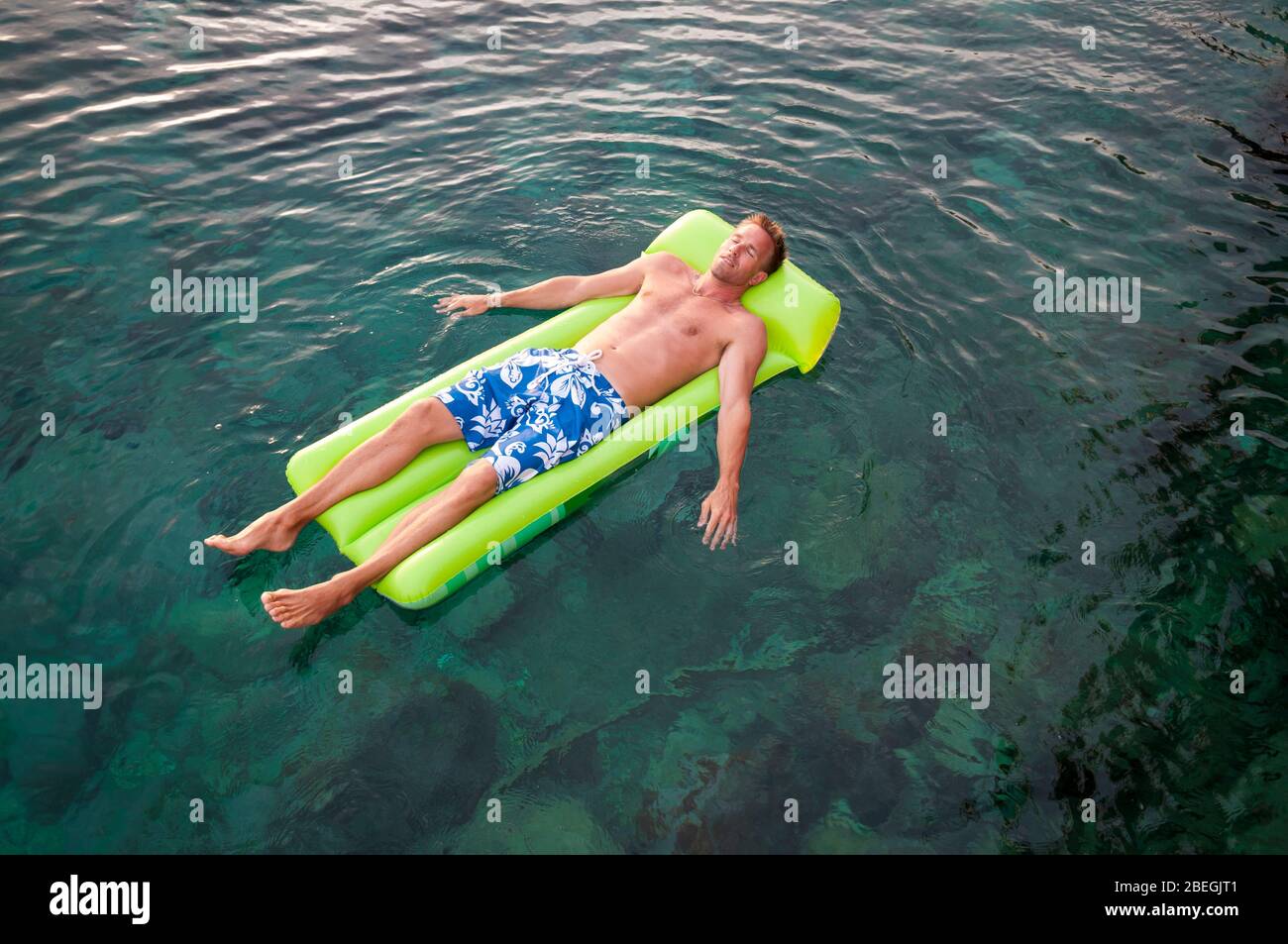 Overhead full length view of man relaxing on a green inflatable lilo ...