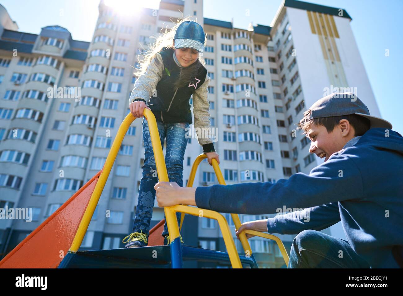 Children play on the playground next to a condominium. Swing, slide ...