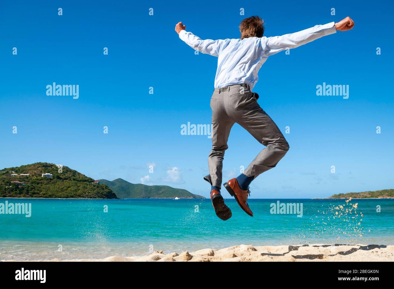 Excited businessman celebrating on a tropical beach jumping into the ...