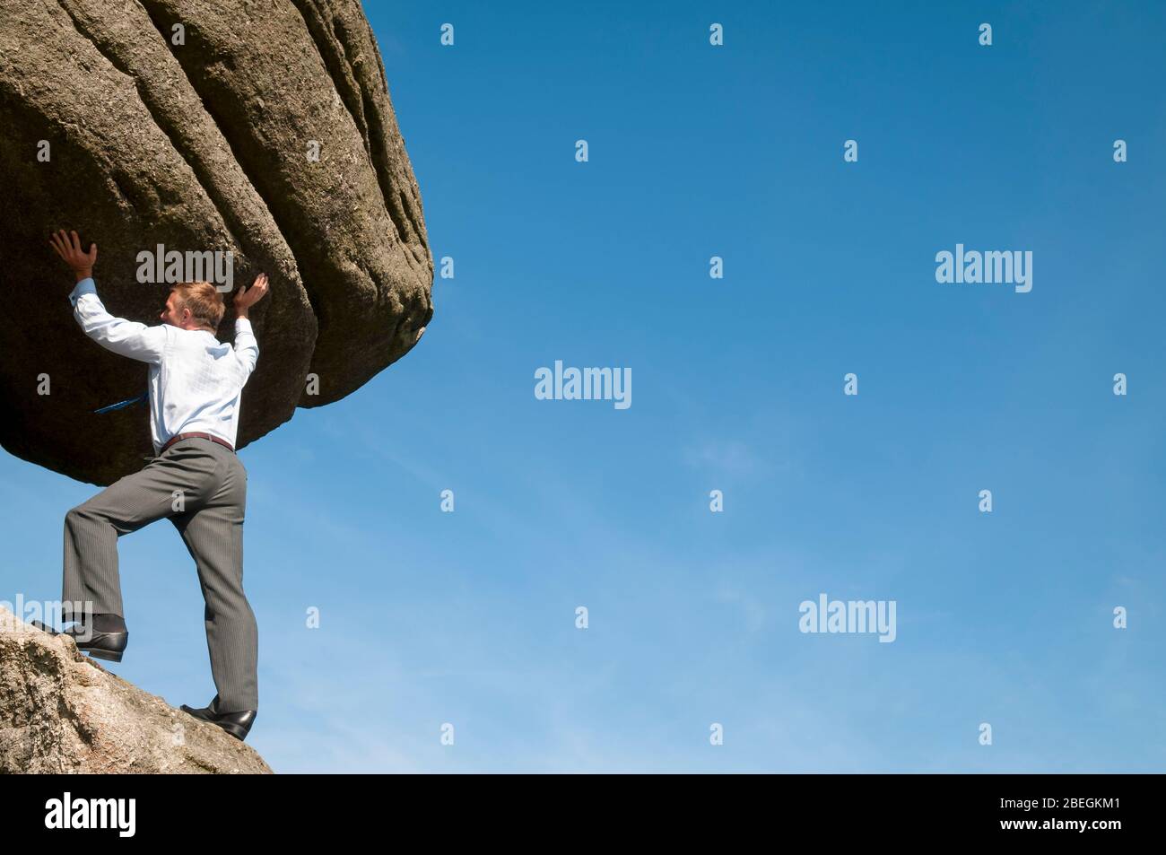 Strong businessman lifting massive rock boulder into blue sky copy ...