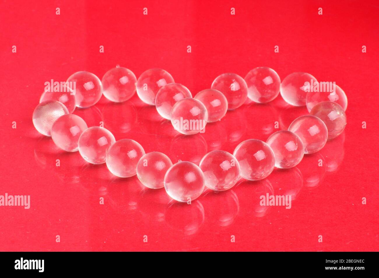Crystal glass balls assembled in heart shape on the red background ...