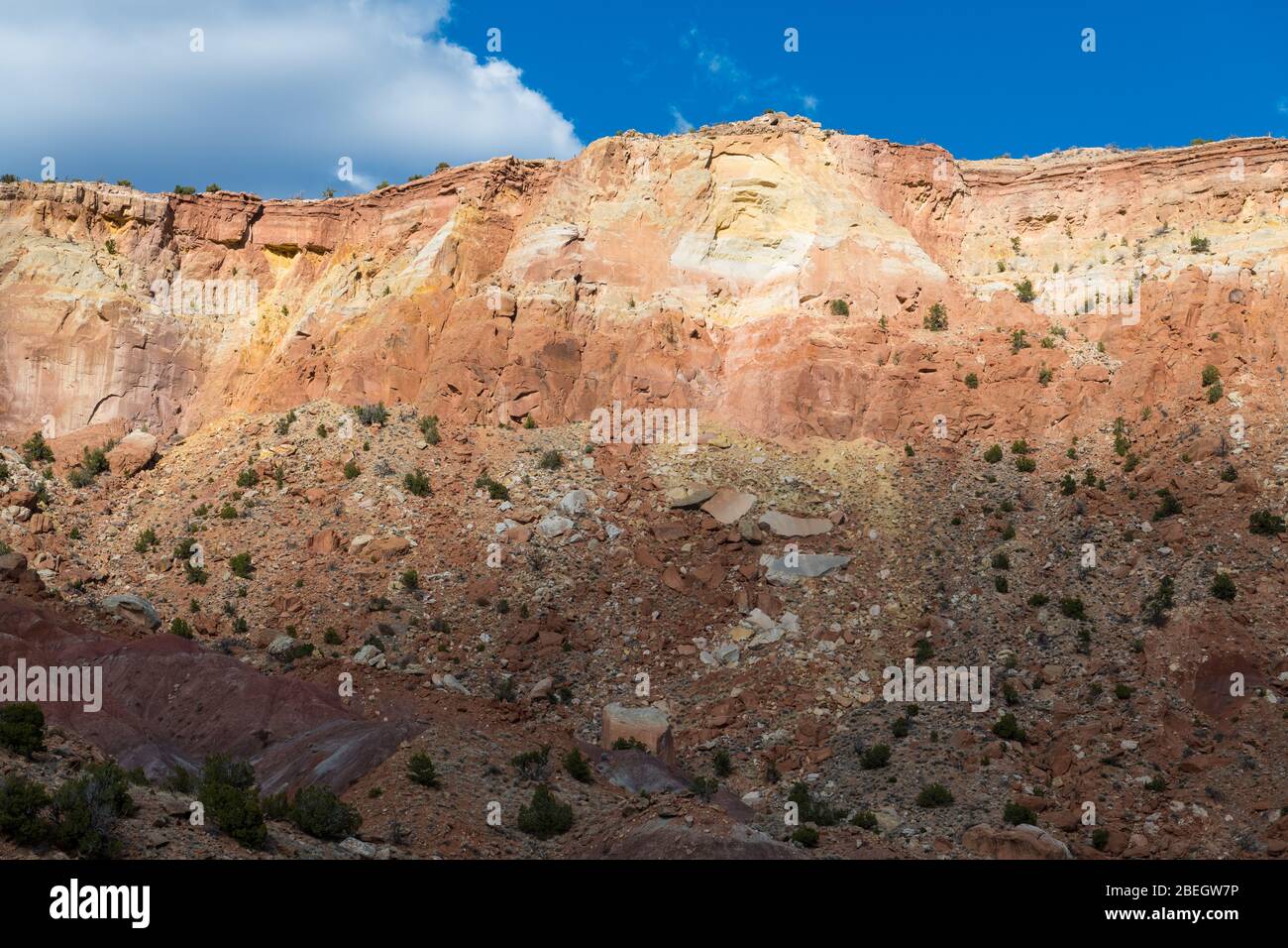 A colorful desert cliff face illuminated a break in the clouds in the ...