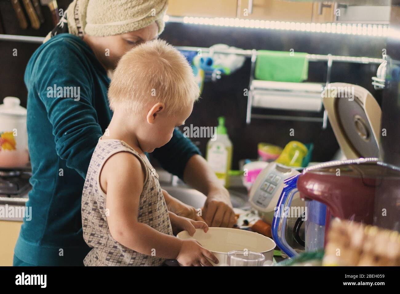 Mom with her 2 years old child cooking in the kitchen, casual lifestyle ...