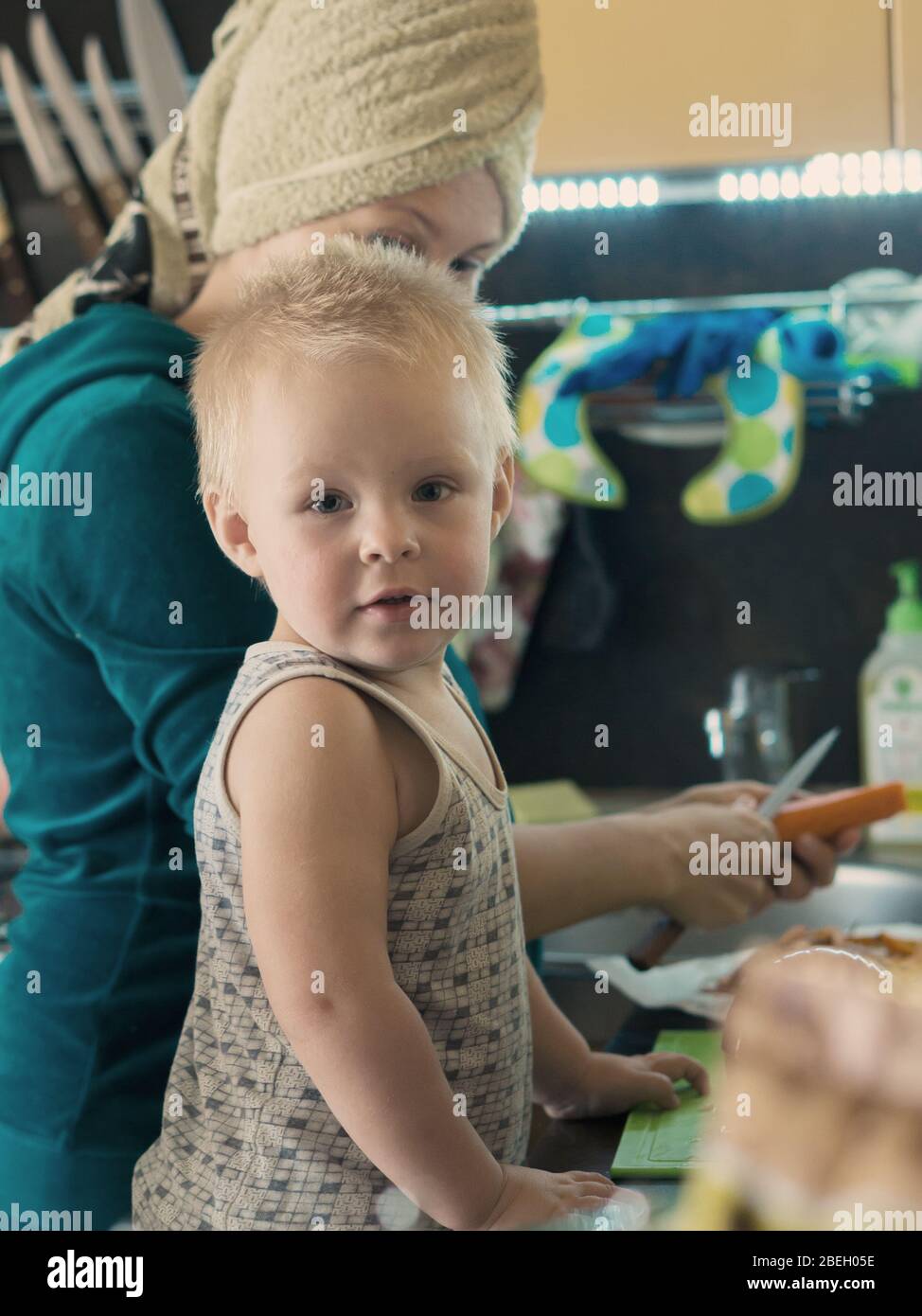 Mom with her 2 years old child cooking in the kitchen, casual lifestyle ...