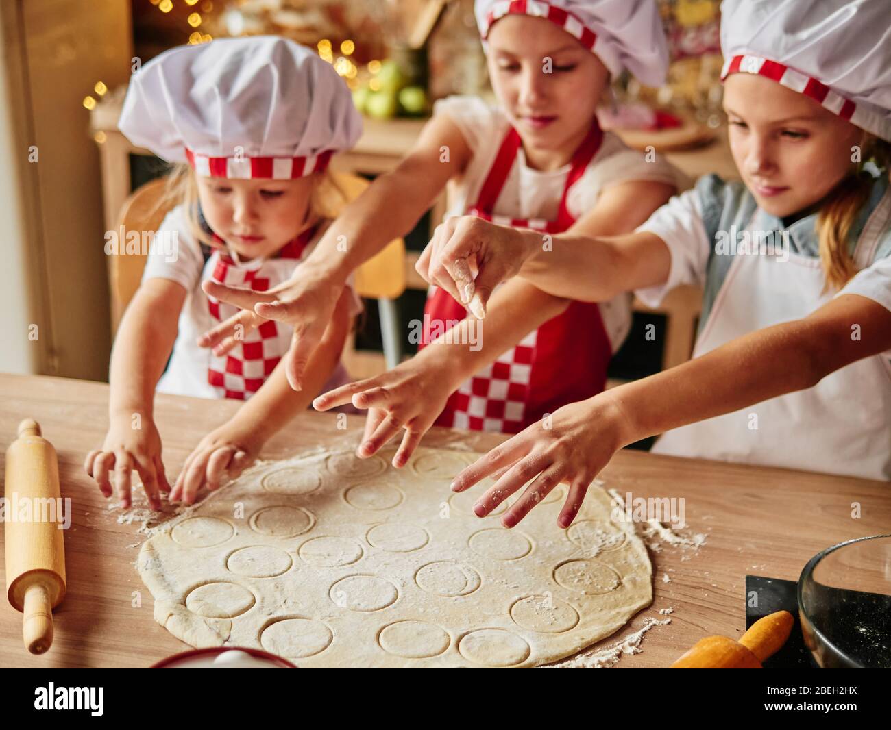 Three little chefs enjoying in the kitchen making cakes. Girls at the ...