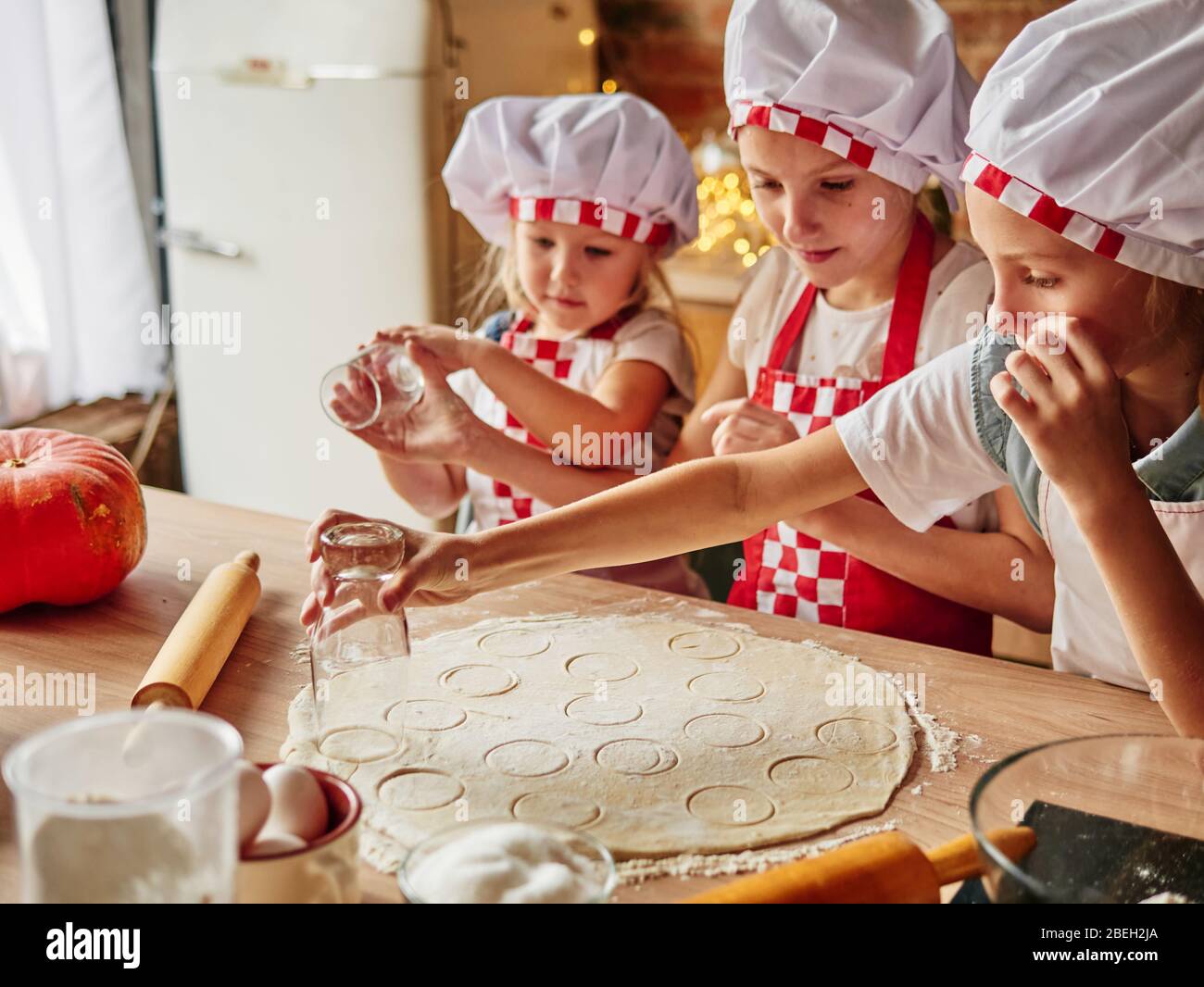 Three little chefs enjoying in the kitchen making cakes. Girls at the ...