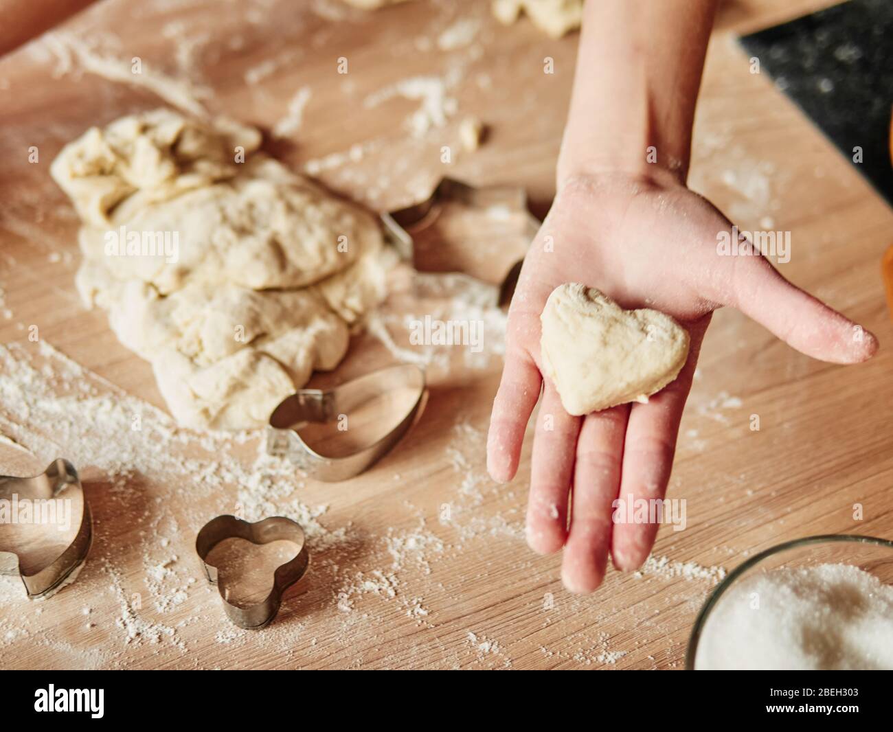 kids hands holding dough in heart shape top view. Baking ingredients on ...