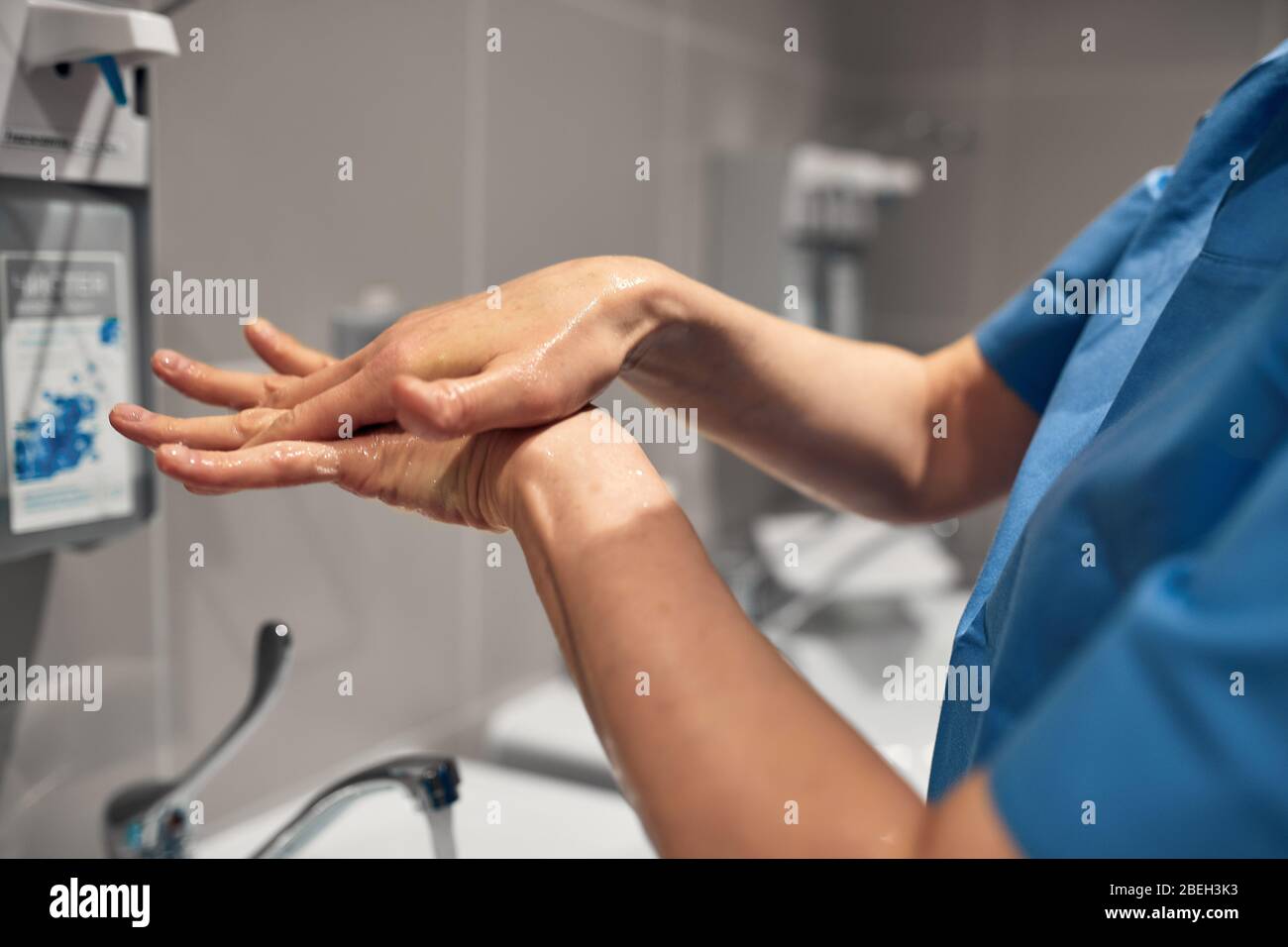 Close-up of a doctor washing his hands using a disinfectant dispenser ...