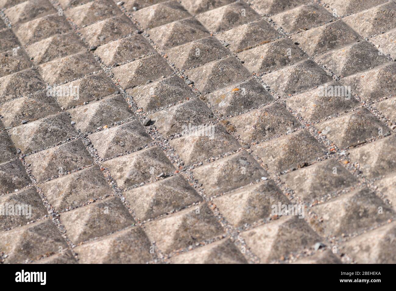 Stone pyramid type paving, that seperates a footpath from the road on ...
