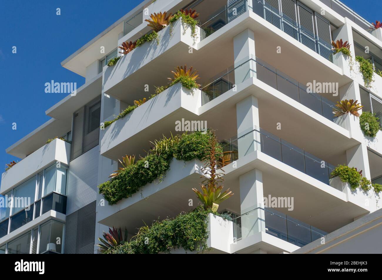 White building with green plants on balconies. Green sustainable ...