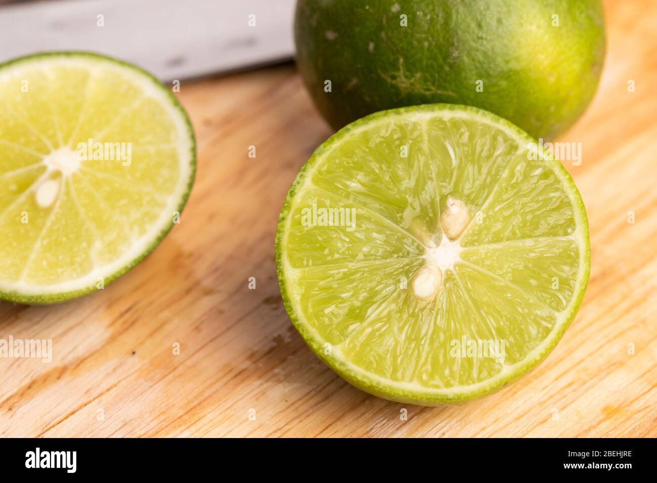 Close up a half of the green lime and seed with a knife place on wooden ...