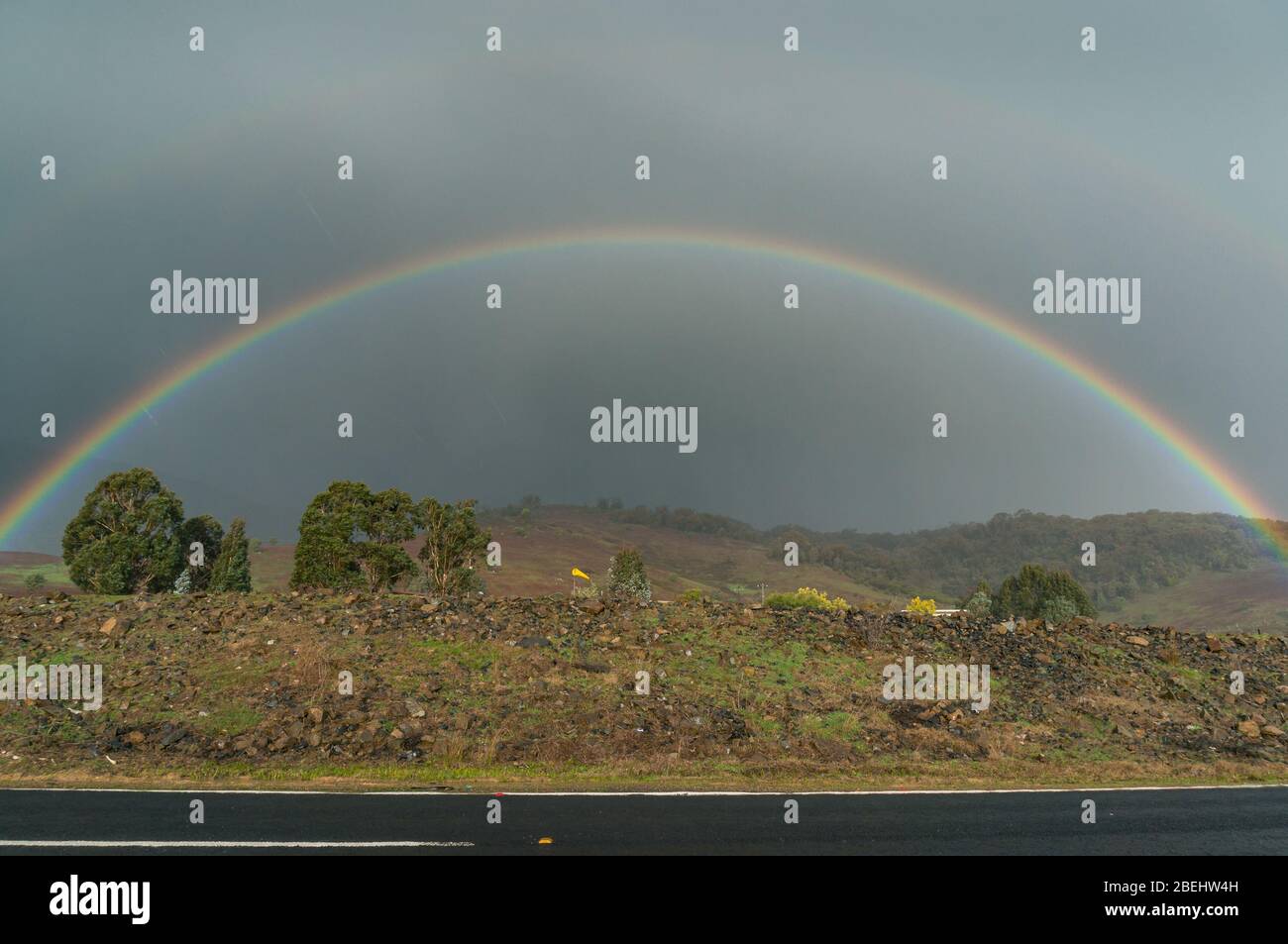 Full arch rainbow against stormy grey sky on the background. Nature ...