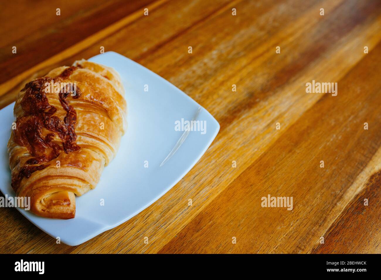 Tasty fresh croissant on a white saucer. Cheese croissant on an empty ...