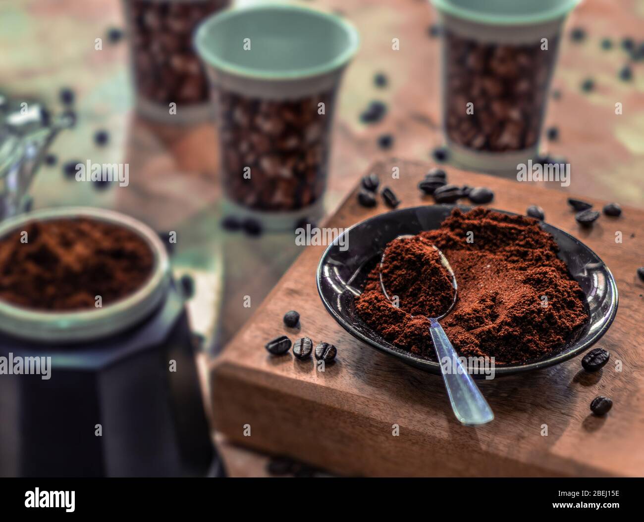 A plate with ground coffee and a spoon on a table, surrounded by coffee ...
