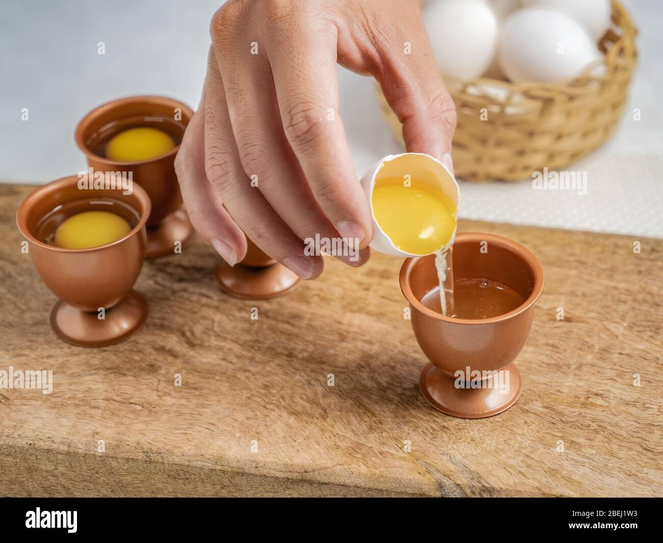 A hand pouring an egg into a copper egg cup Stock Photo - Alamy