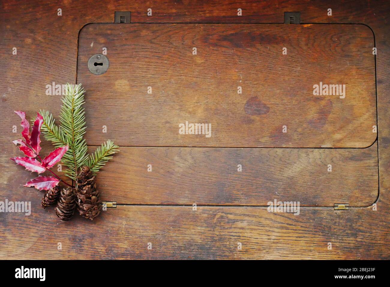 Pine cones, fronds and holly on a retro wooden table, space for text ...
