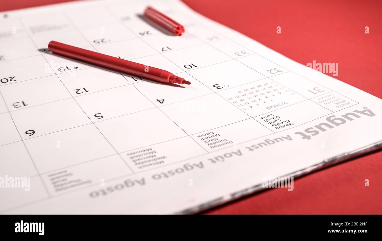 Closeup of a red pen on a open calendar. Calendar open on a august page ...