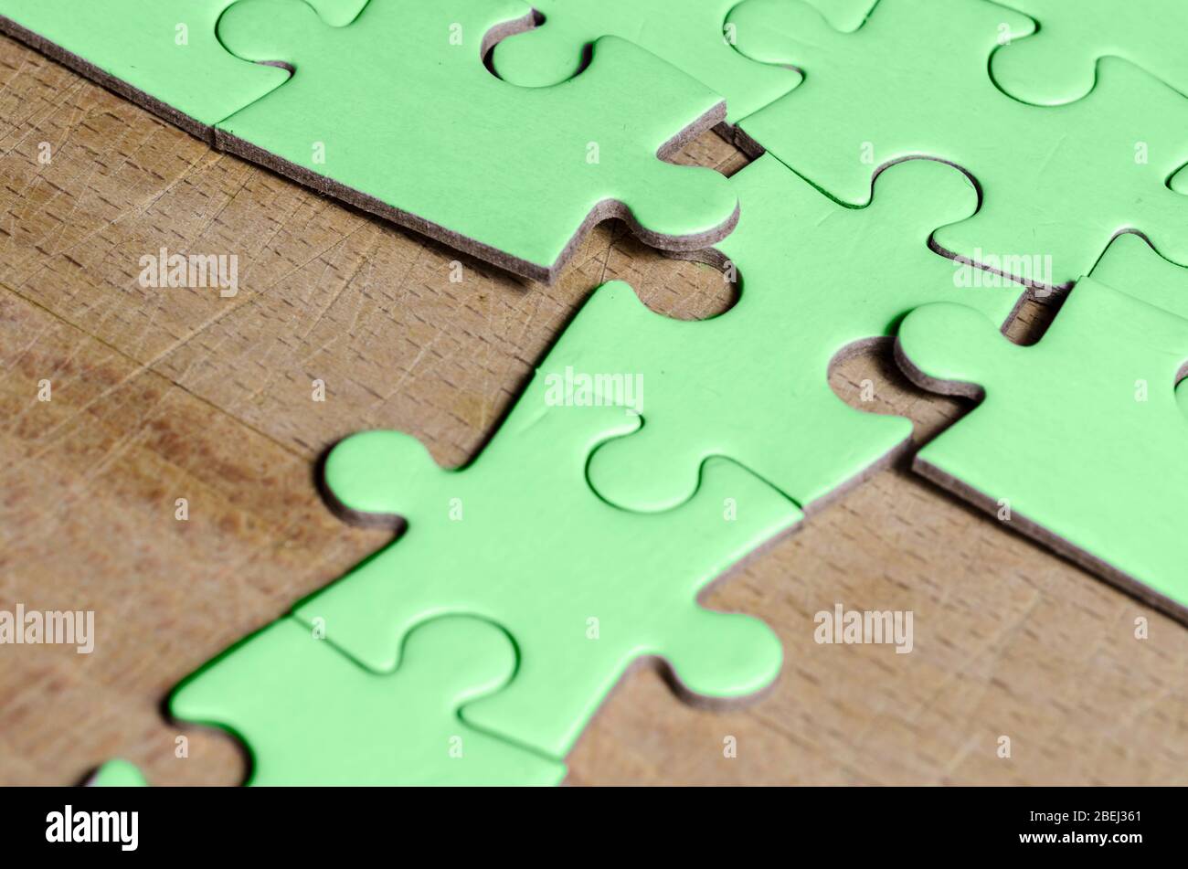 white jigsaw/puzzle with a row in wrong position, over wooden table ...