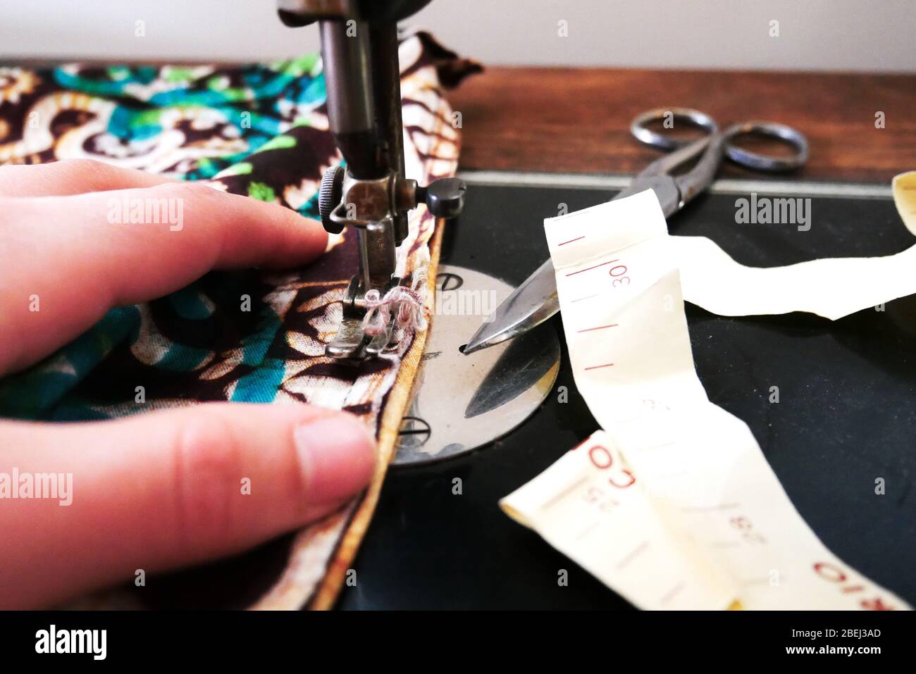 Close-up of person using vintage sewing machine with fabric, scissors ...