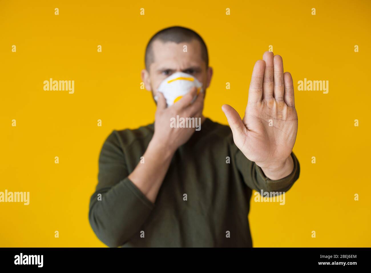 Alerted caucasian man wearing a sterile mask and gesturing the stop ...