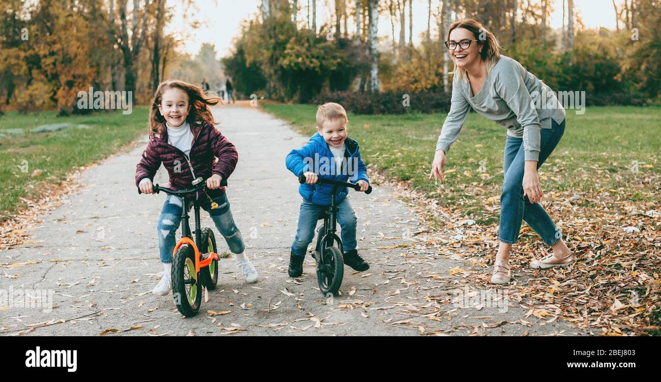 Lovely mother having a walk in the park with her children teaching them ...