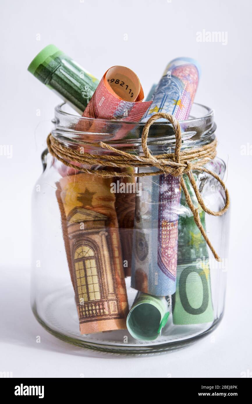 Glass jar with euro notes isolated on white background, euros rolled up ...