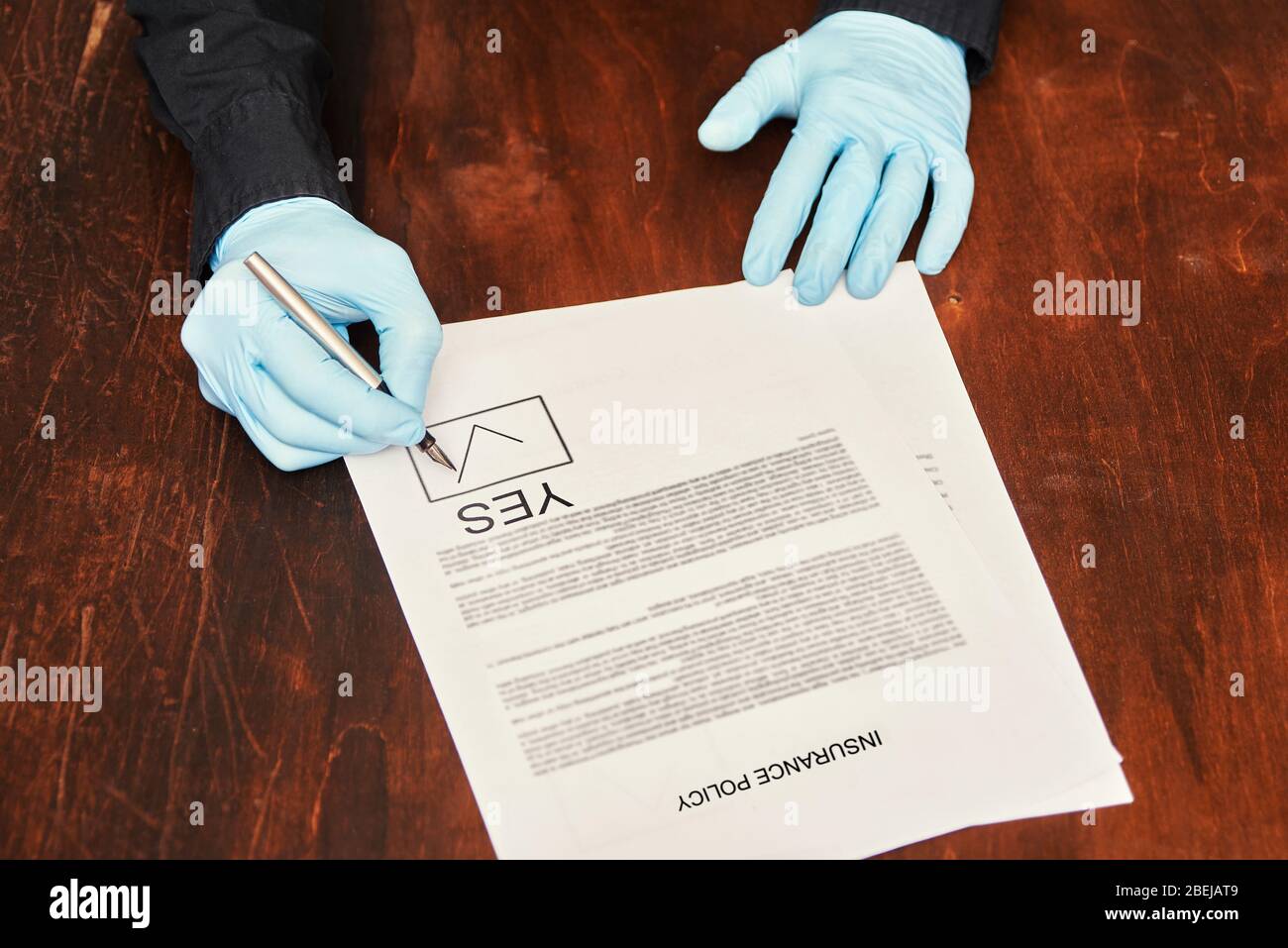 signature of the insurance policy form. man in latex gloves signs a ...
