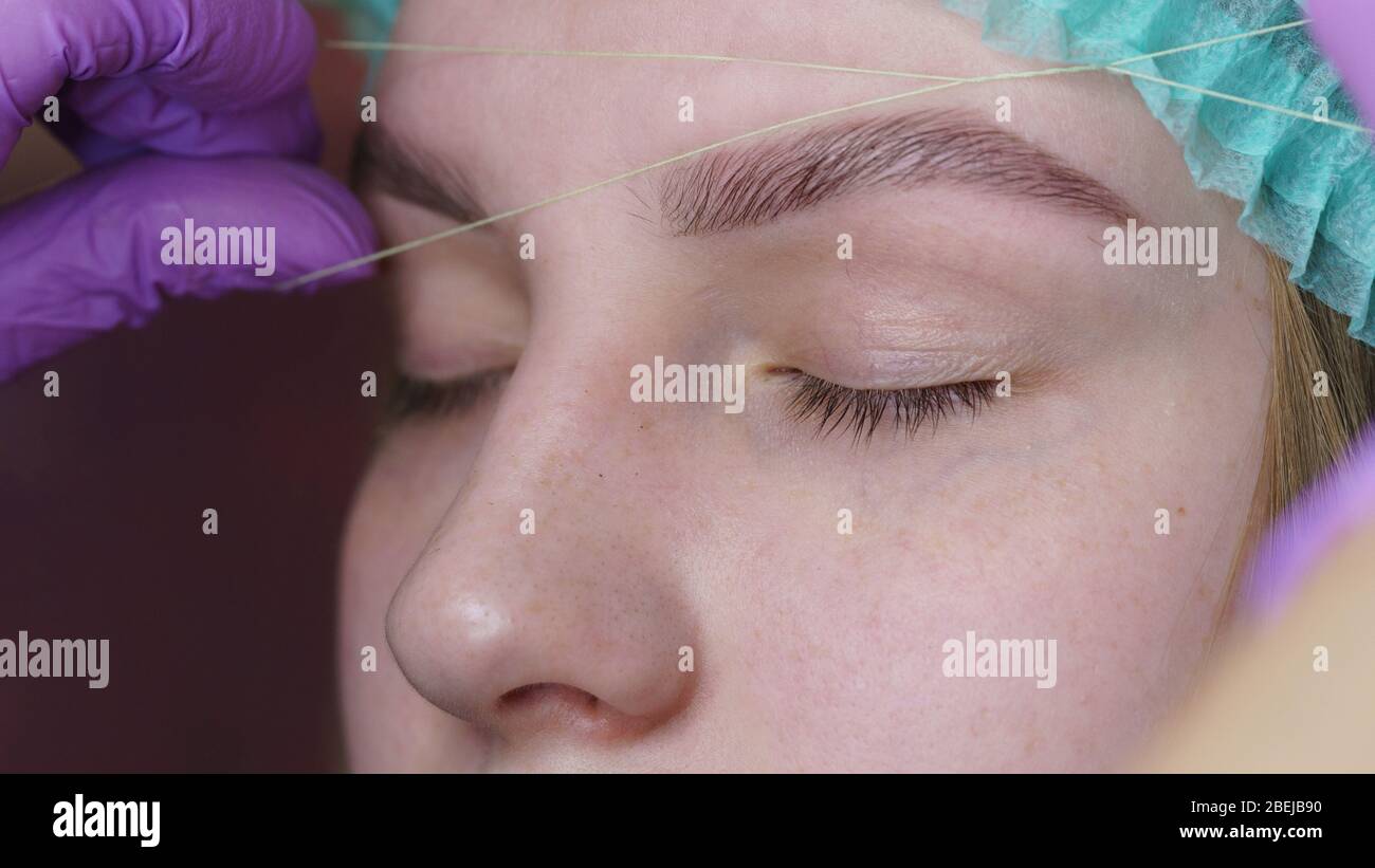 Close-up of female eye with thriding. Triding popular thread eyebrow correction technology ...