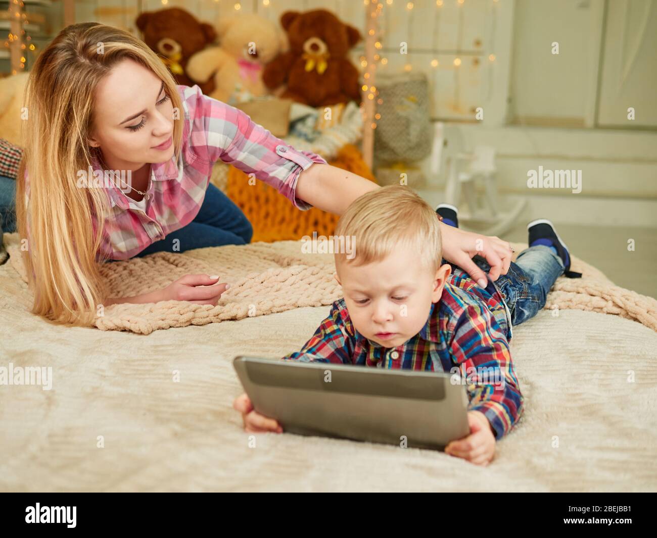 Mother takes care of a kid watching tab, family ralationships Stock ...
