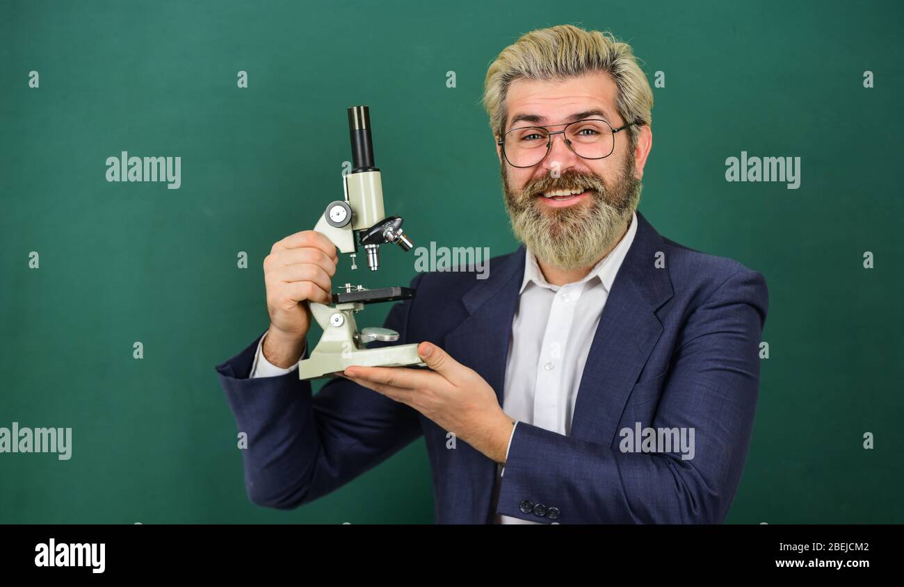 Fascinating research. Teacher with microscope. Man hipster classroom ...