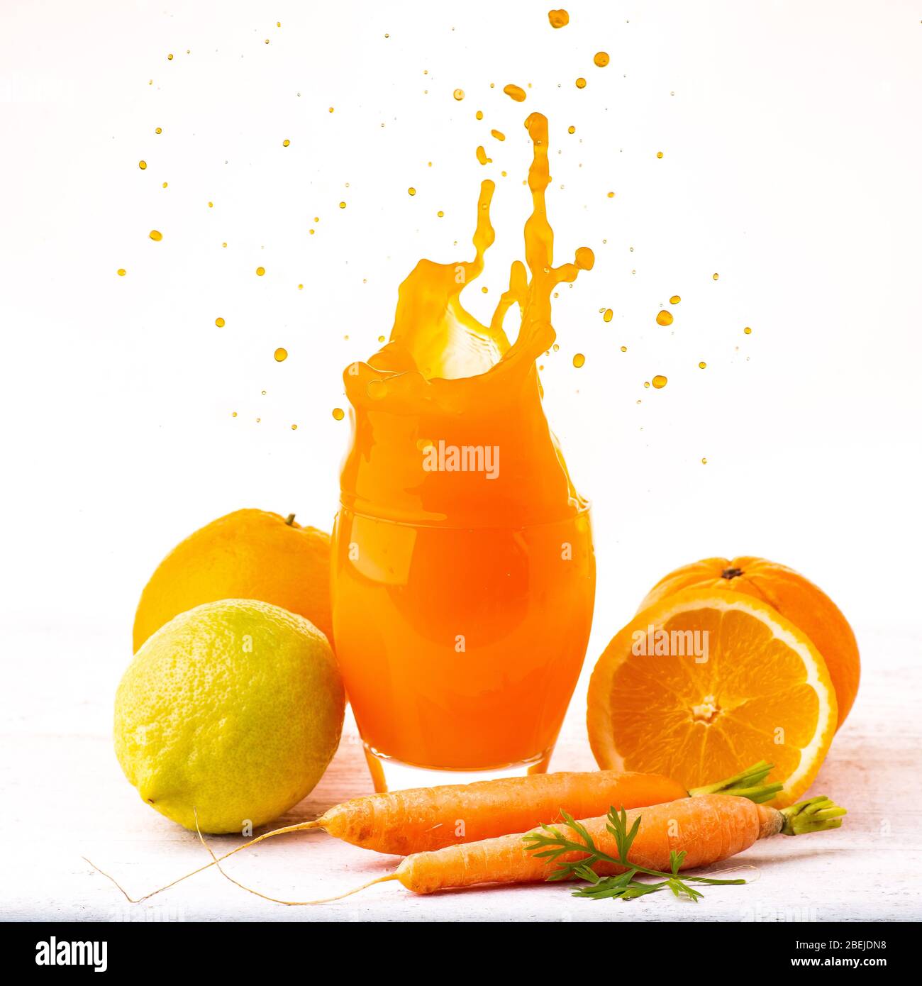 fresh citrus and carrot juice in the glass with splash. White ...