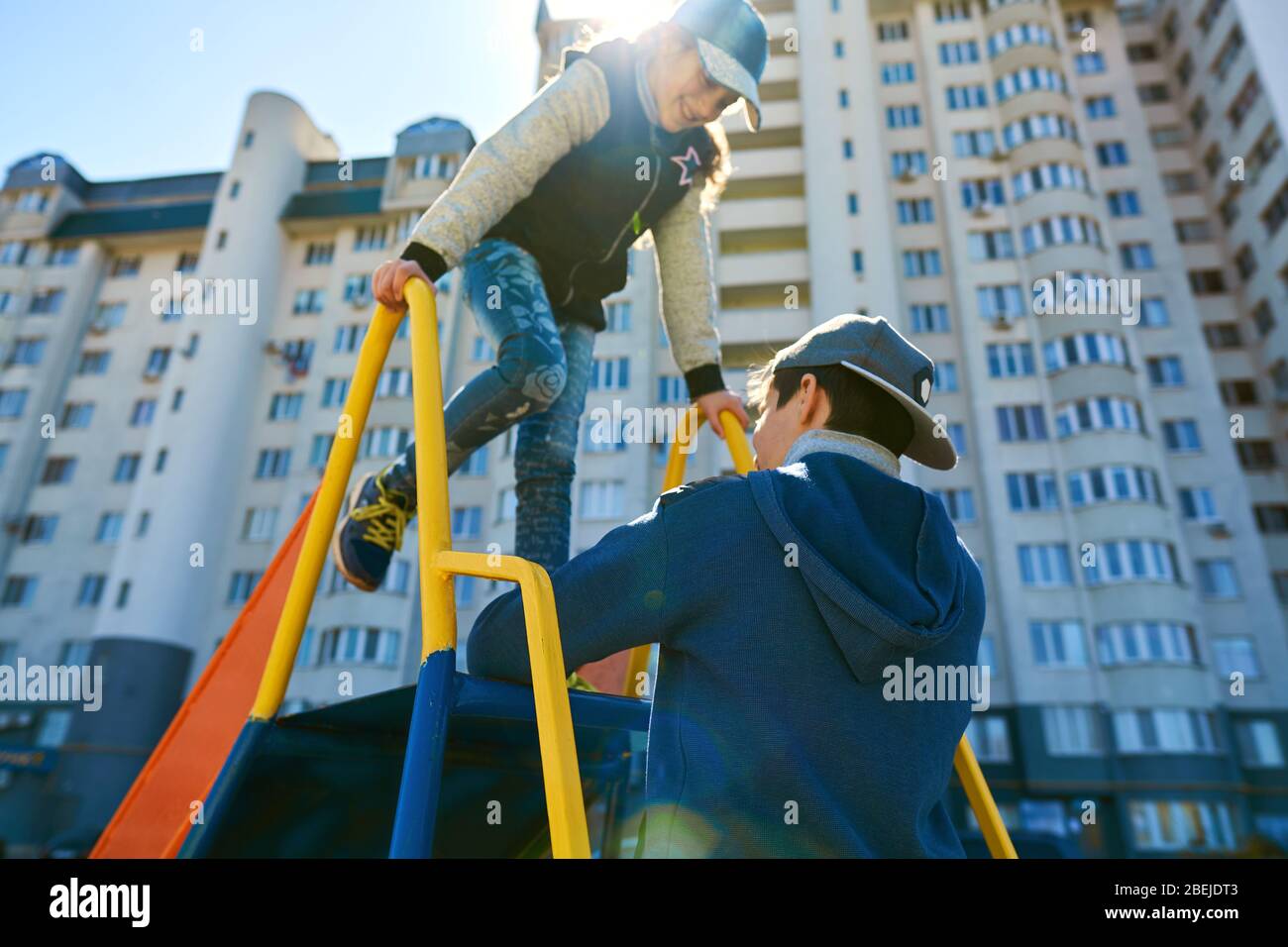 Children play on the playground next to a condominium. Swing, slide ...