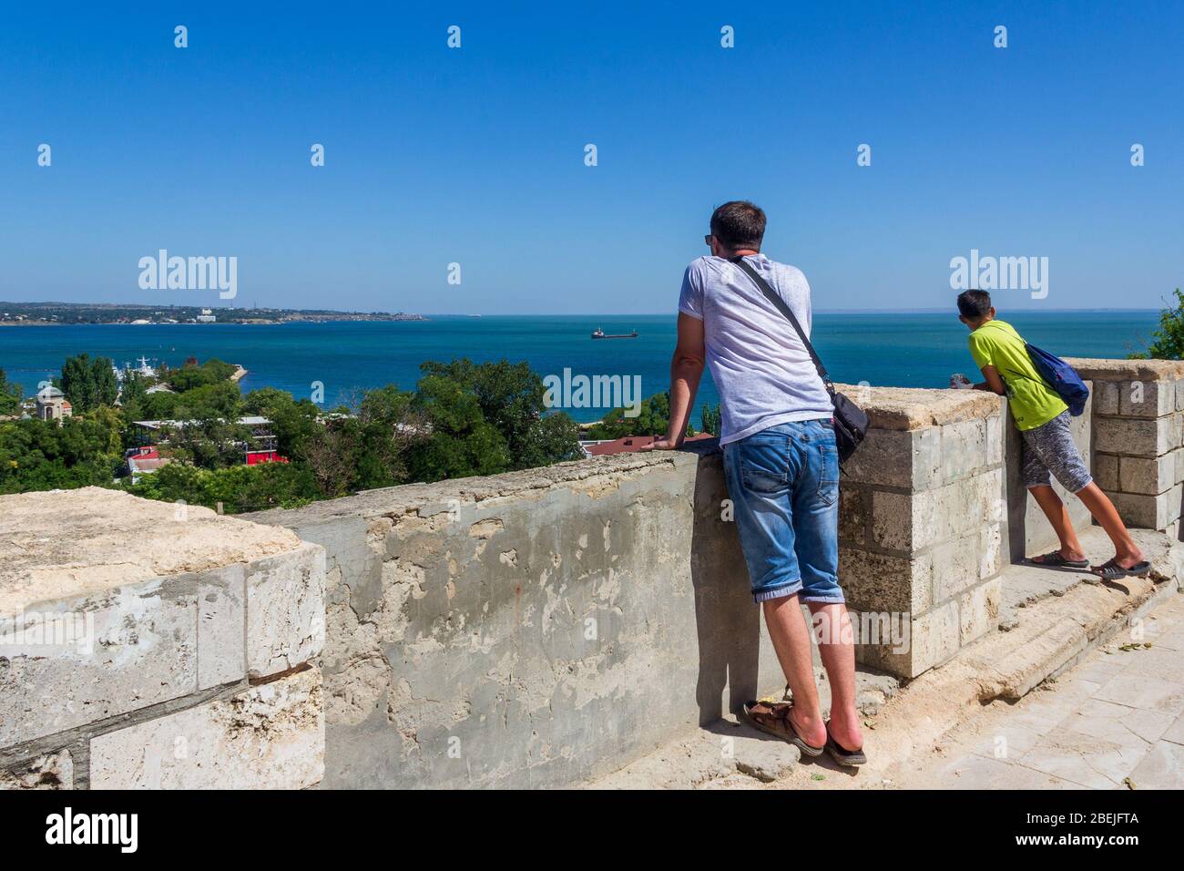 a father and son look at the summer landscape with a view of the ...