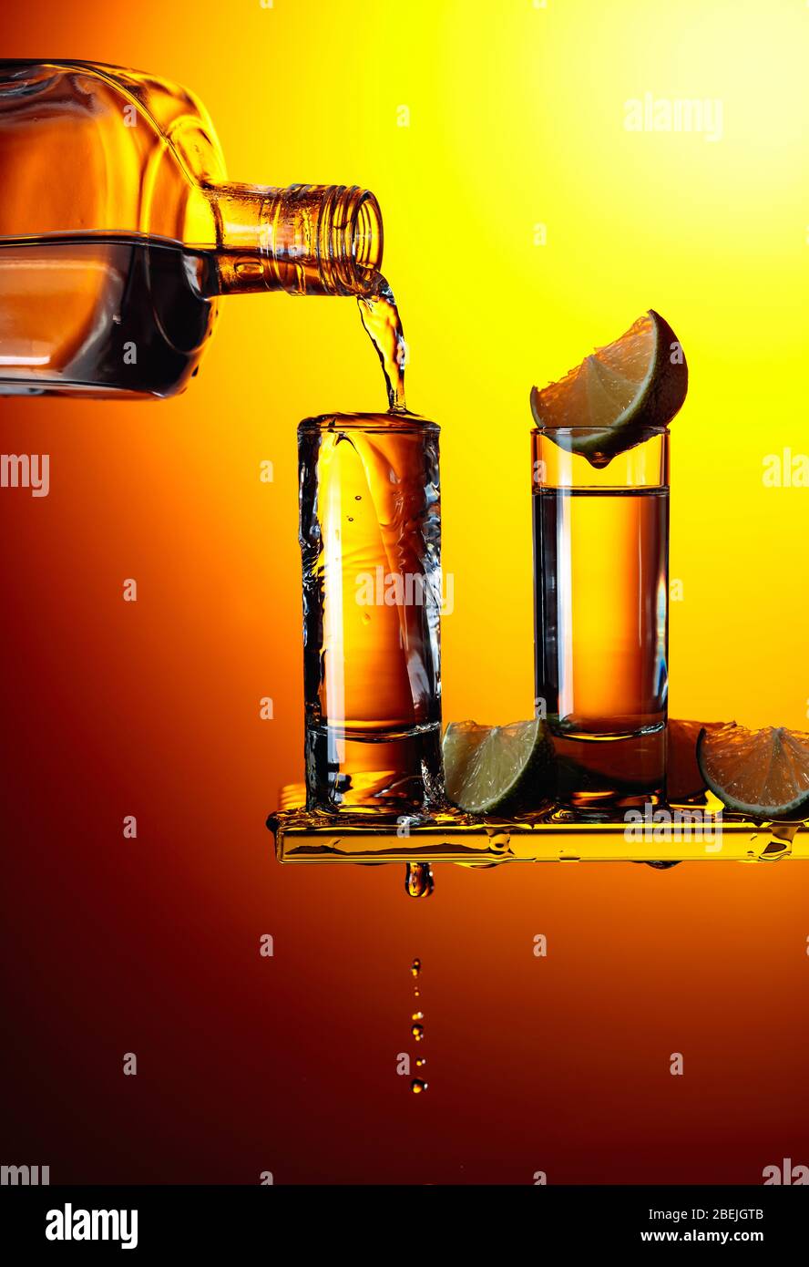 Tequila with lime slices on a yellow background. Pouring a strong ...