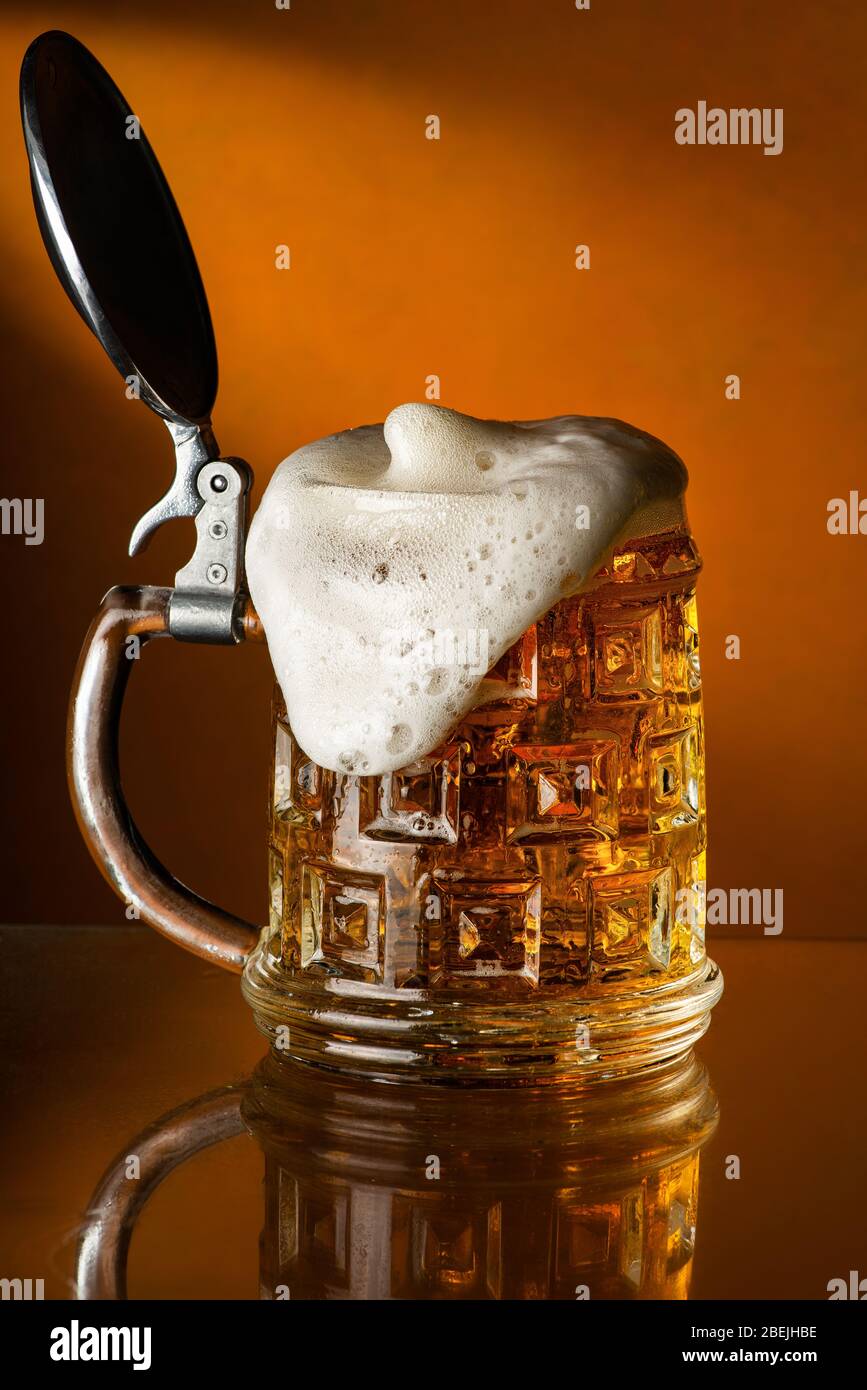 fresh and frothy beer overflowing from the glass mug Stock Photo - Alamy