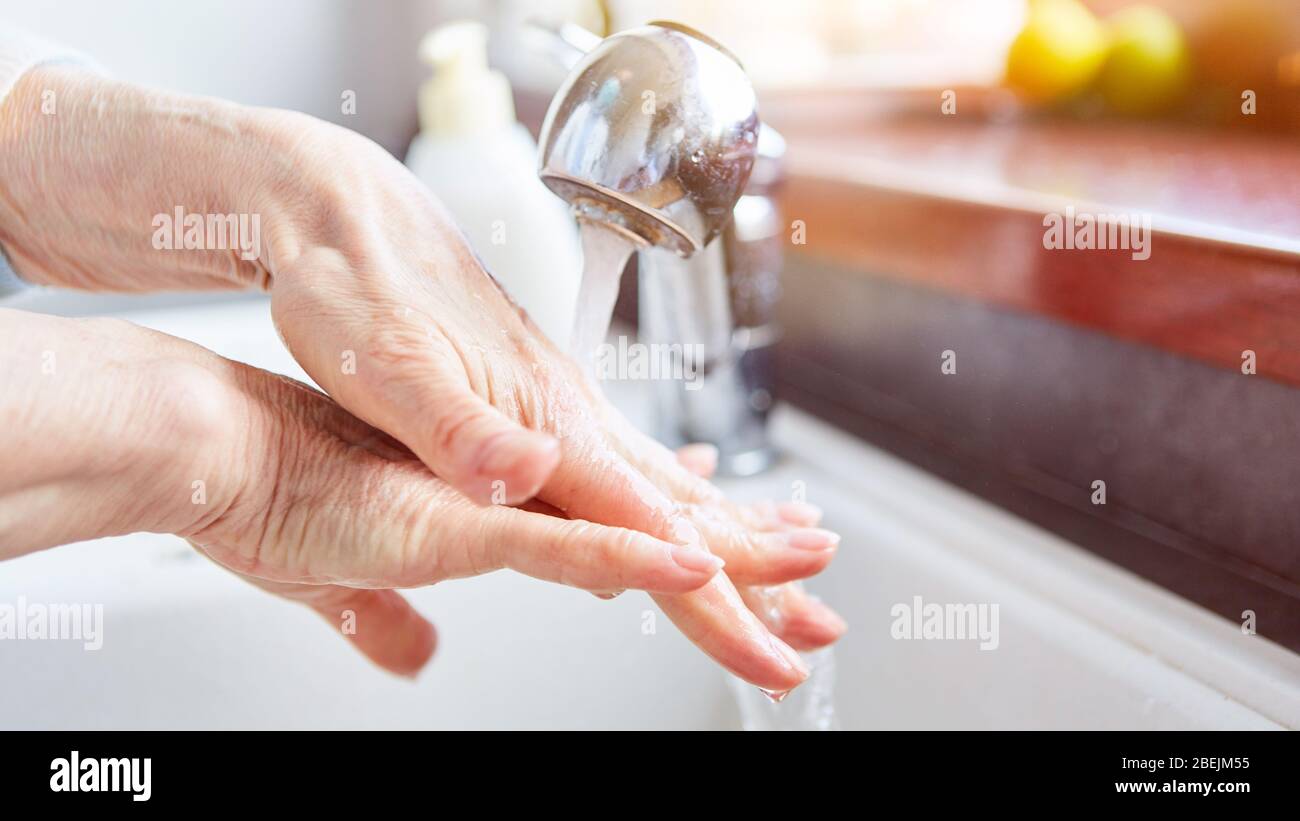 Seniors washing their hands with soap in the spaces between their hands ...