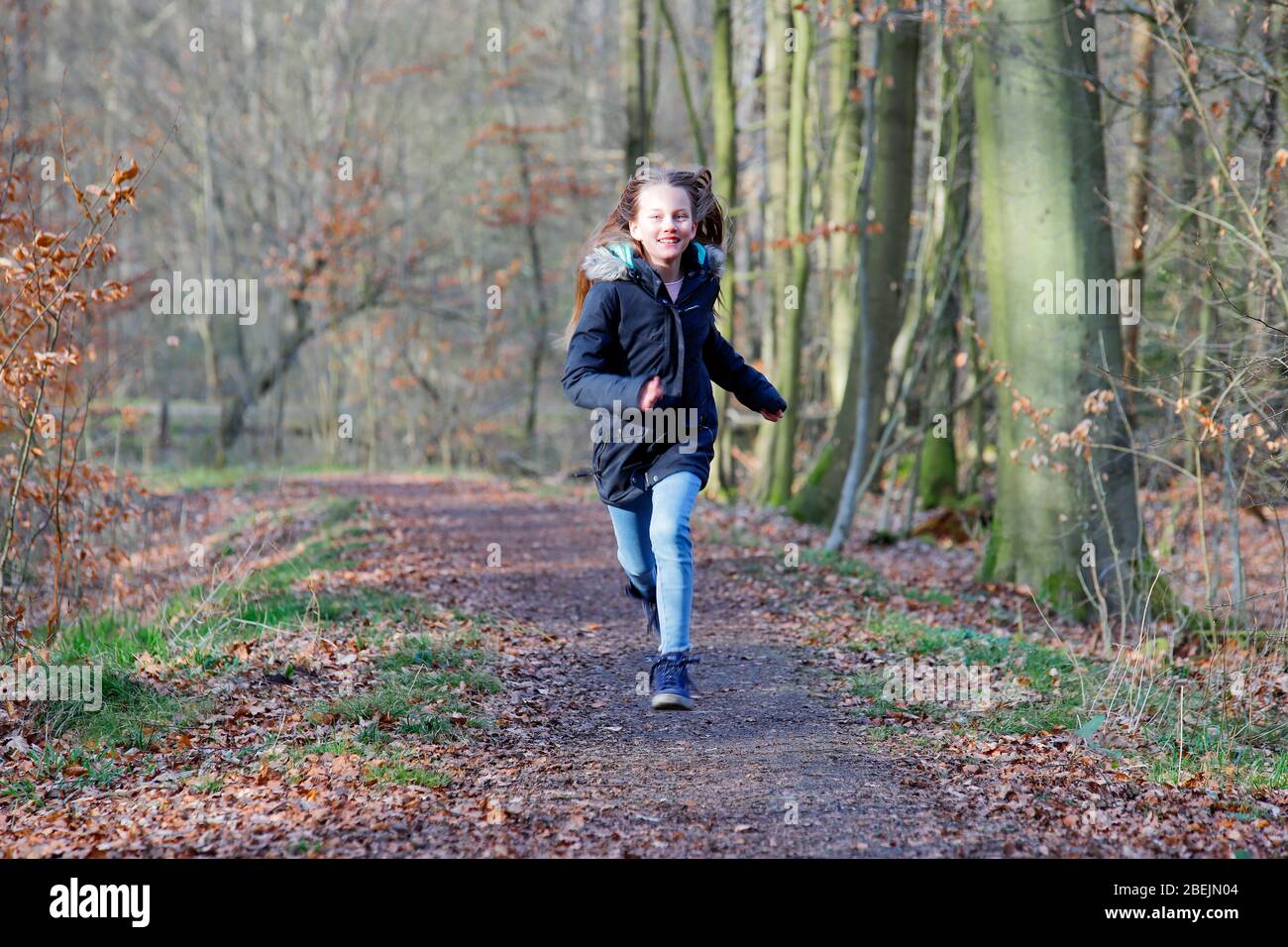 A girl is running on a path in the woods Stock Photo - Alamy