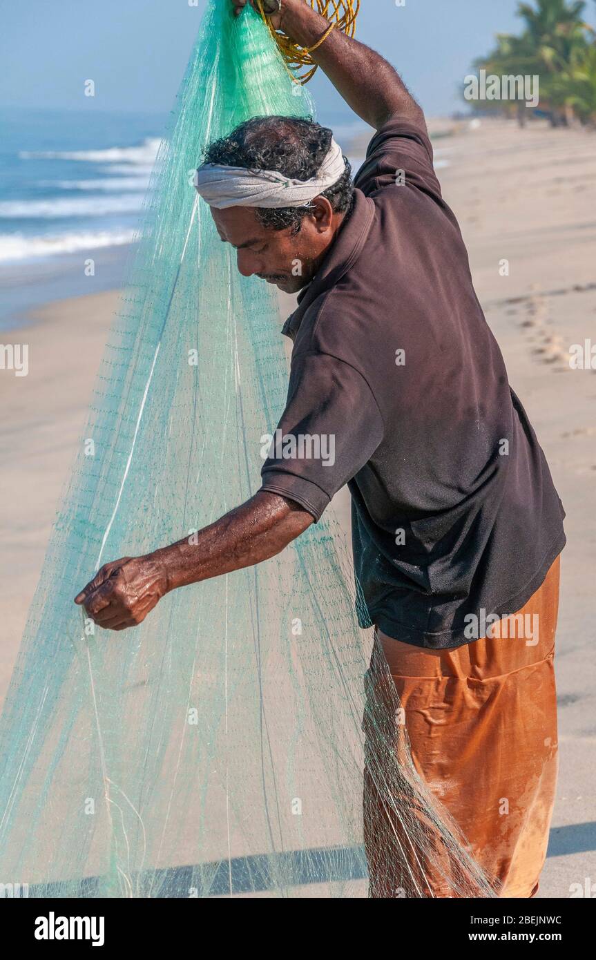 Fisherman on the beautiful Marari Beach in early morning fishing with a ...