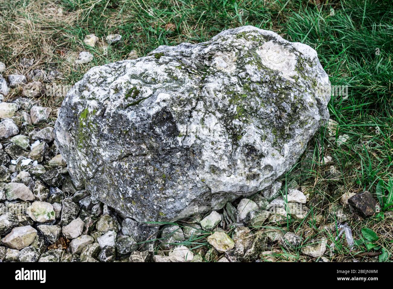 Big old stone laying on small stones and on the green grass Stock Photo ...