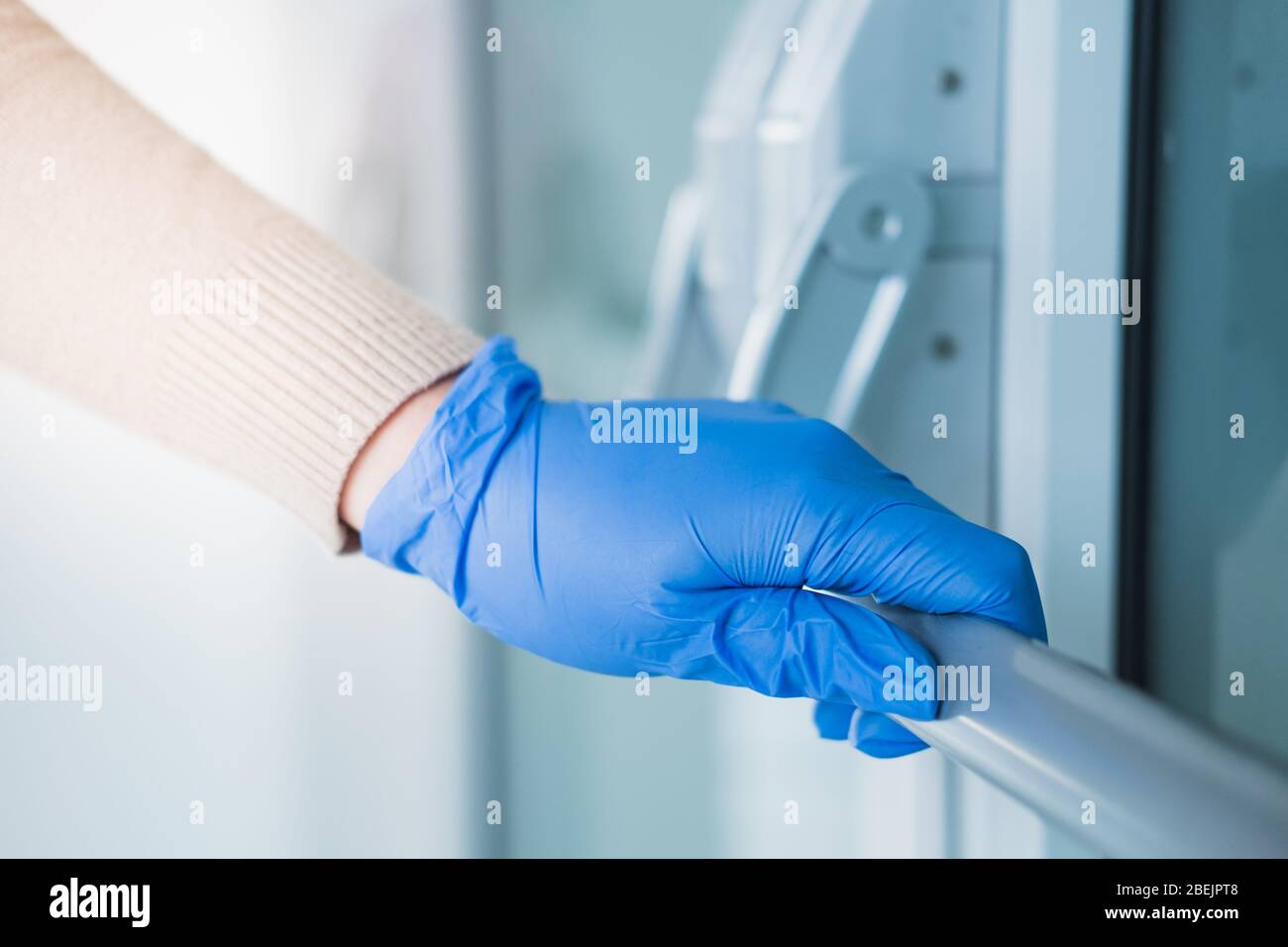 Hand in a rubber glove touches the handlebar of a door. Personal ...