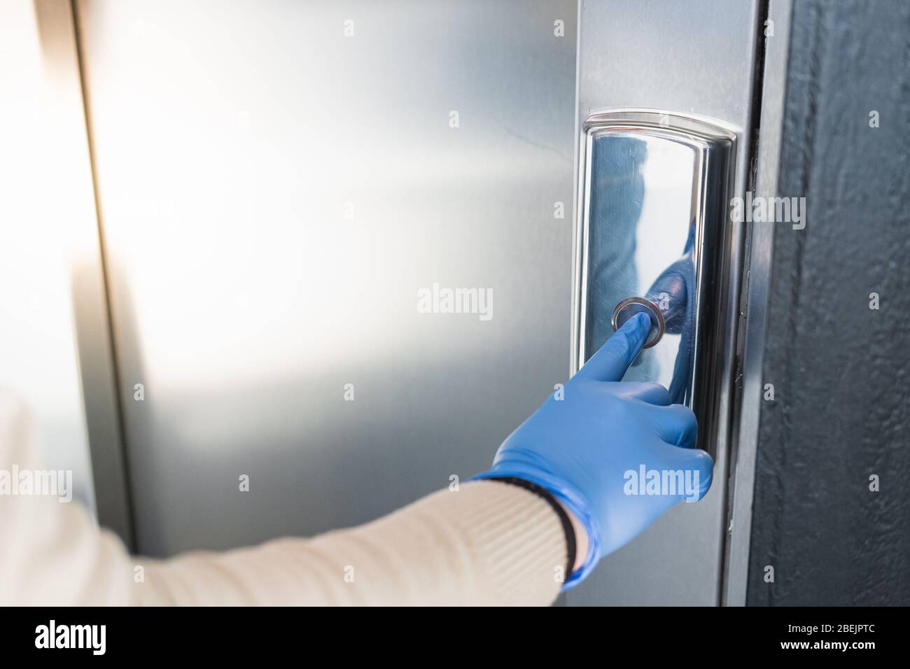 Hand in a rubber glove presses the elevator or lift button. Personal ...